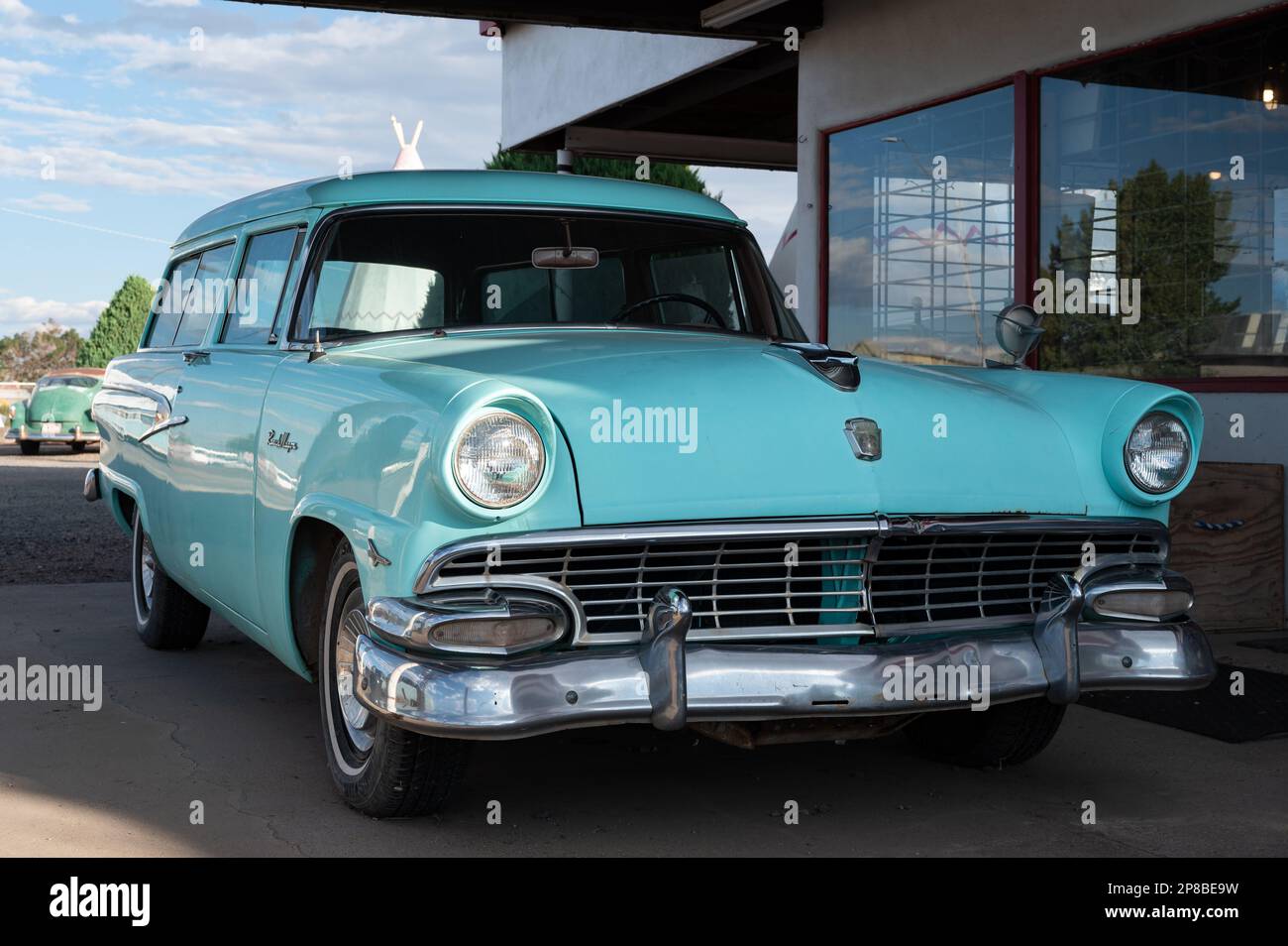 A teal-colored ford ranch wagon is parked in front of a store ...