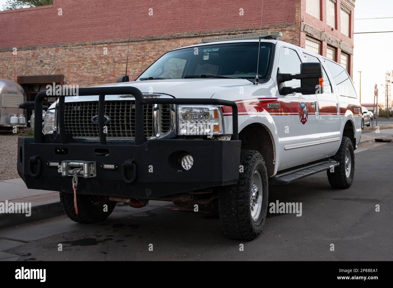 A large white rescue truck is parked in front of a vibrant red building ...