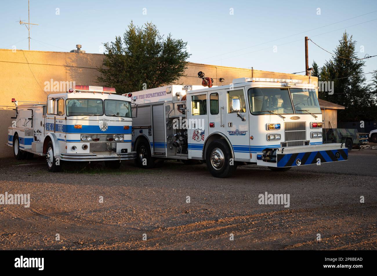 Two white fire trucks are parked next to each other in a parking lot ...