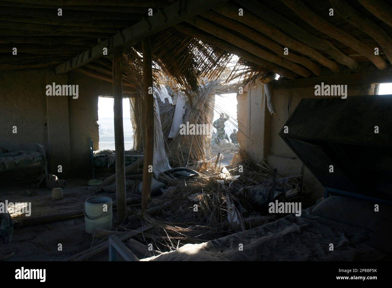 Soldiers stand outside a building damaged by a weapons cache explosion ...