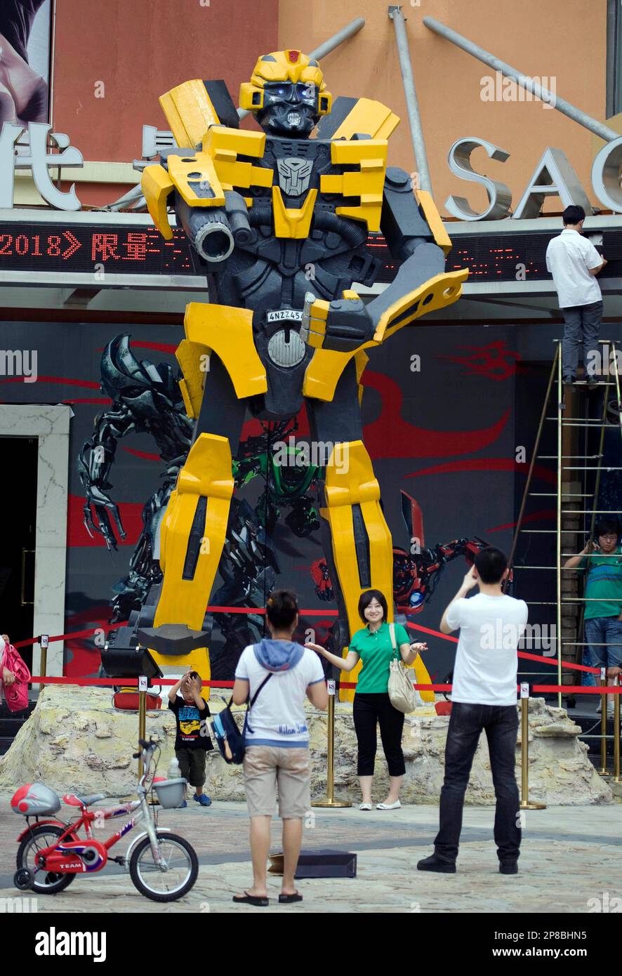 Chinese shoppers pose near a life size model of the bumblebee character ...