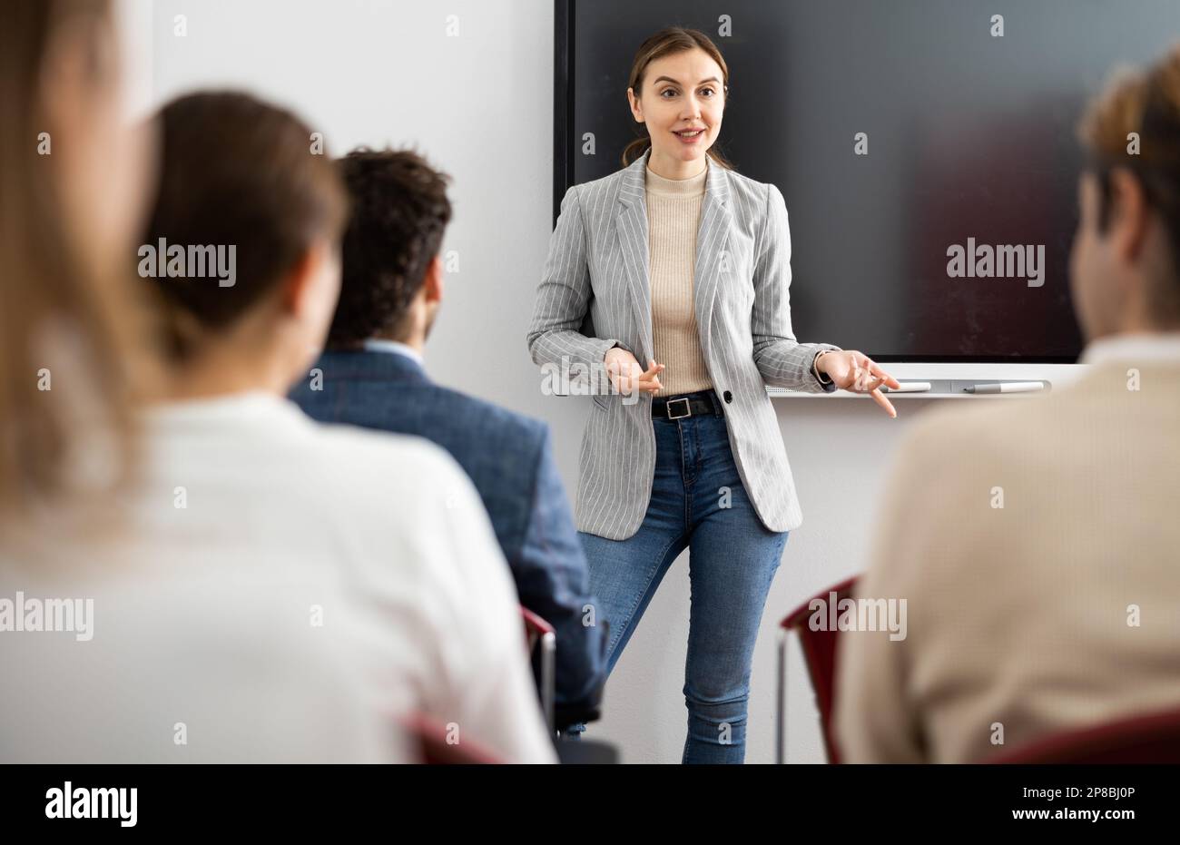 Young female tutor teaching students in college classroom Stock Photo ...