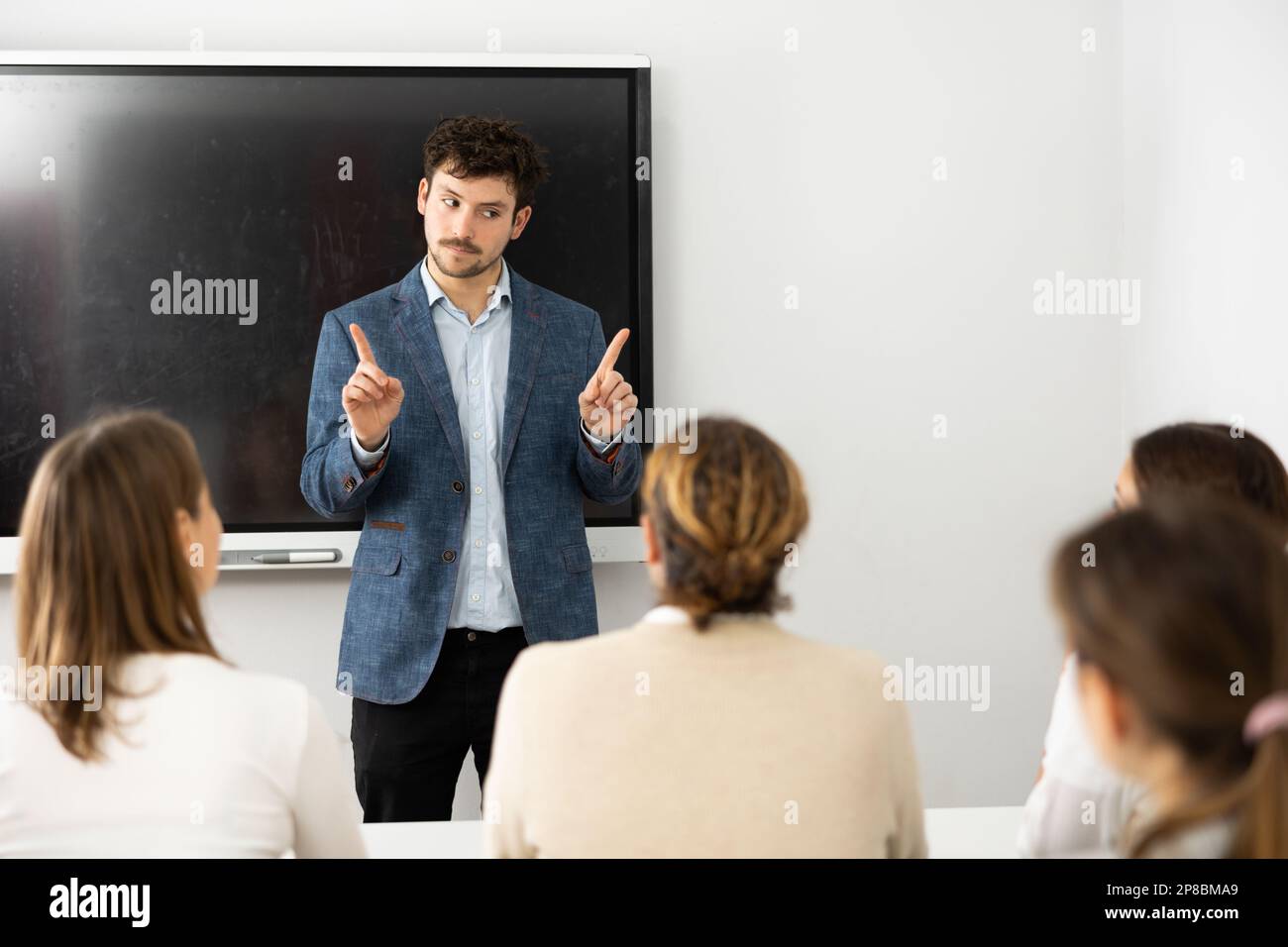 Young male tutor teaching students in college classroom Stock Photo - Alamy