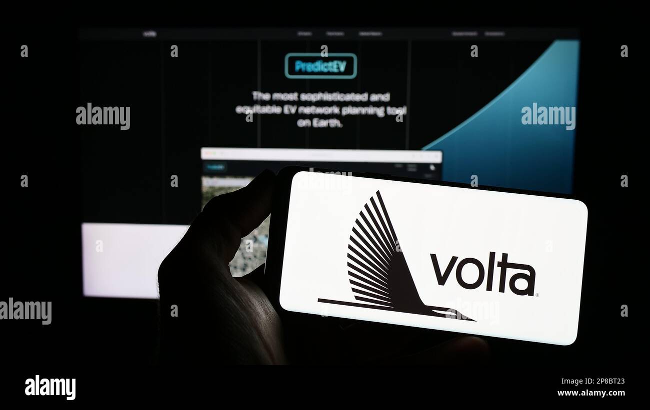 Person holding mobile phone with logo of EV infrastructure company ...