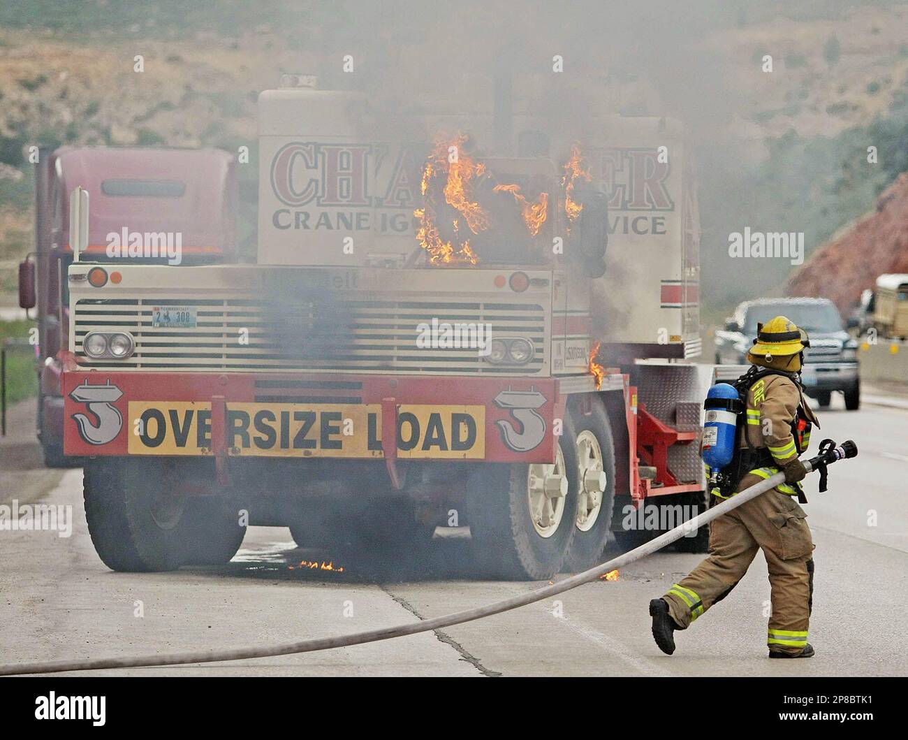 A firefighter prepares to extinguish an I-80 roadside fire involving a ...