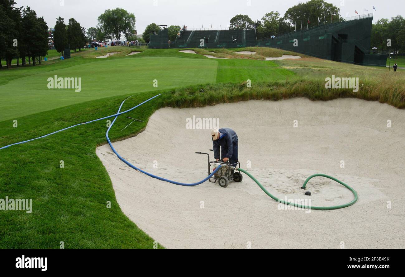 Course worker Brad Camera drains water from the course at the 18th hole ...