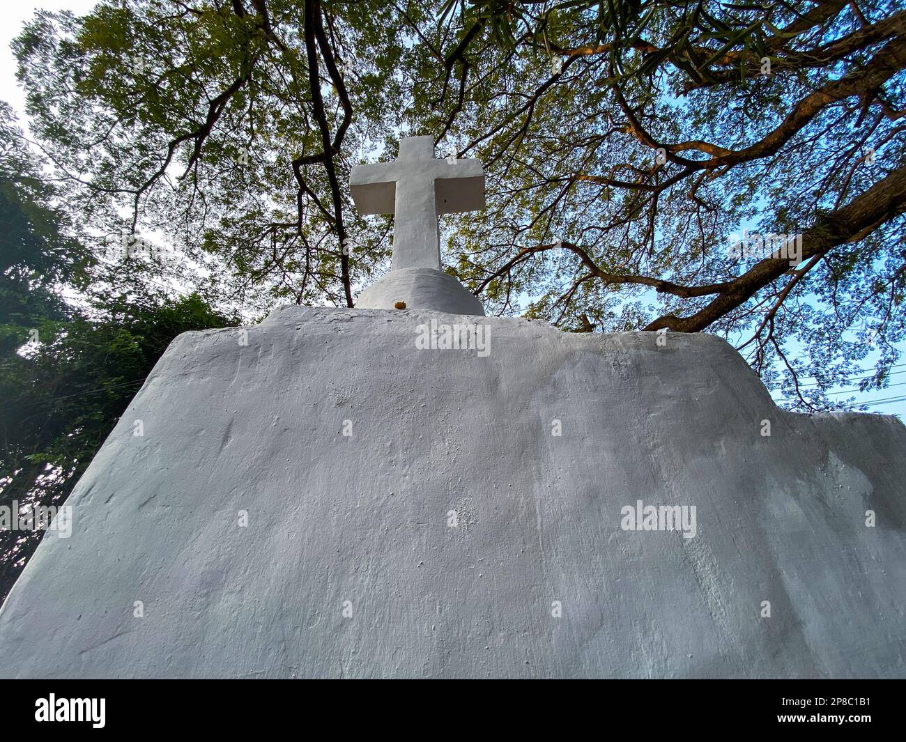Low angle view of a white cross of a small roadside chapel surrounded ...