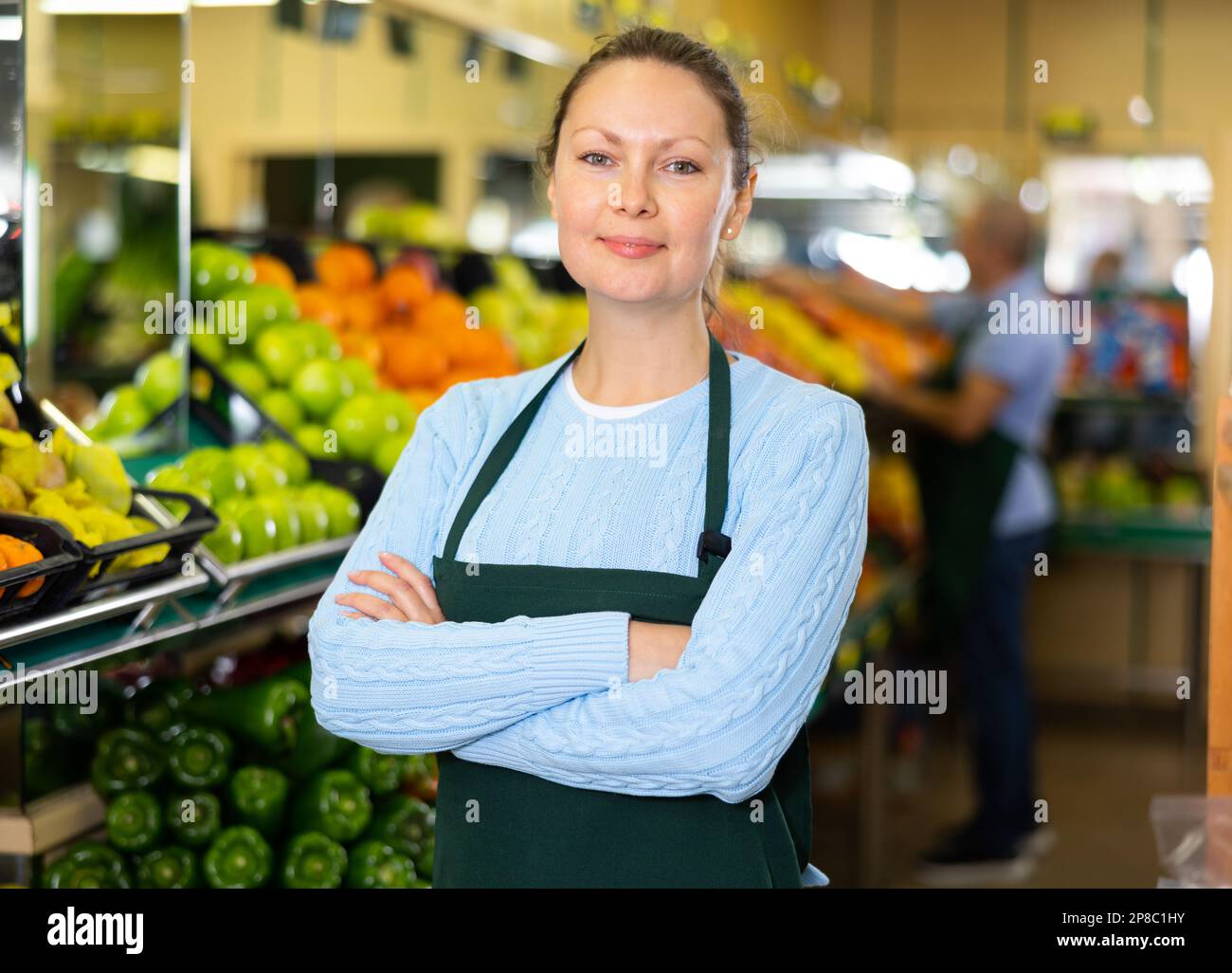 Joyful skilled adult female seller in uniform posing during working day ...