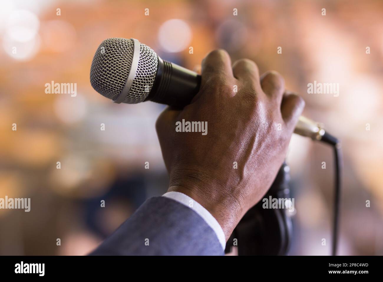 Male hand holding microphone at conference hall Stock Photo - Alamy