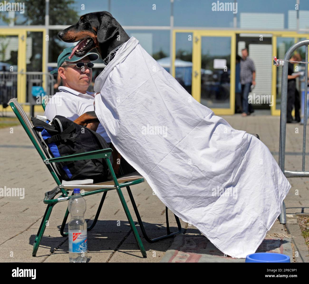 Steffen Patenge sits on a chair beside his Doberman dog who is covered ...