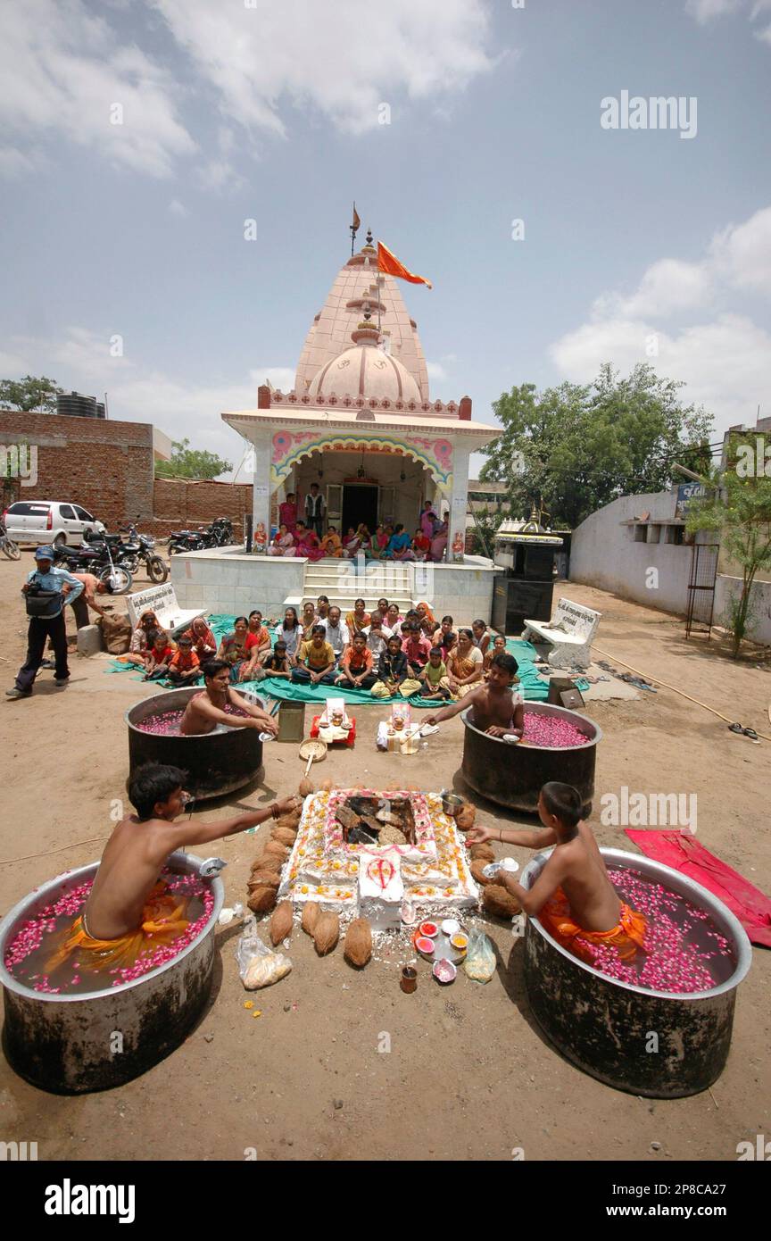 People sit in utensils filled with water to perform parjanya yagya, a ...