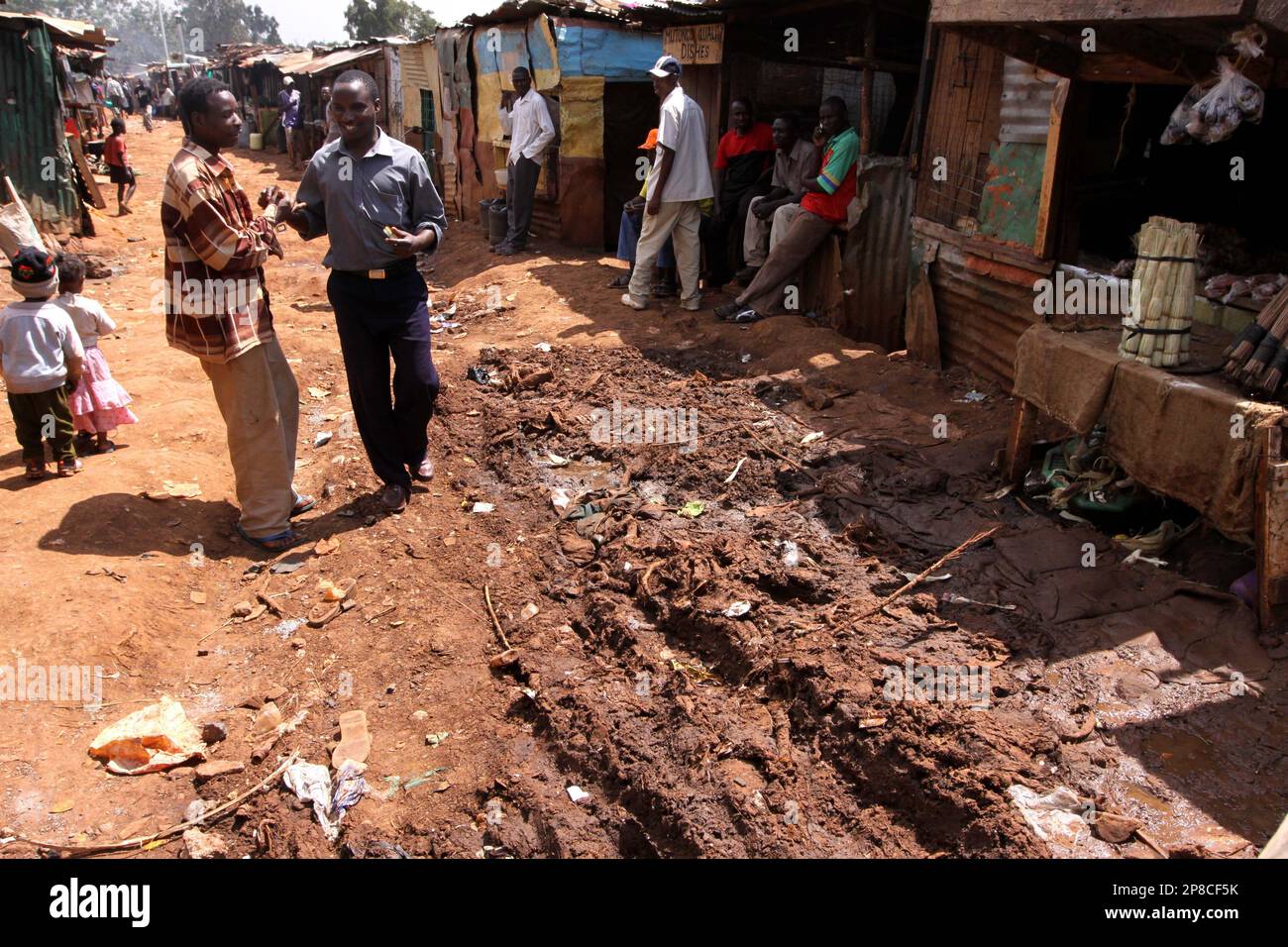Two men greet each other in a muddy street in the Deap Sea slum in ...