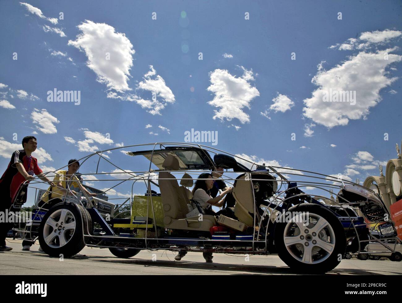 Chinese men push a modern car stripped of its metallic body to showcase ...