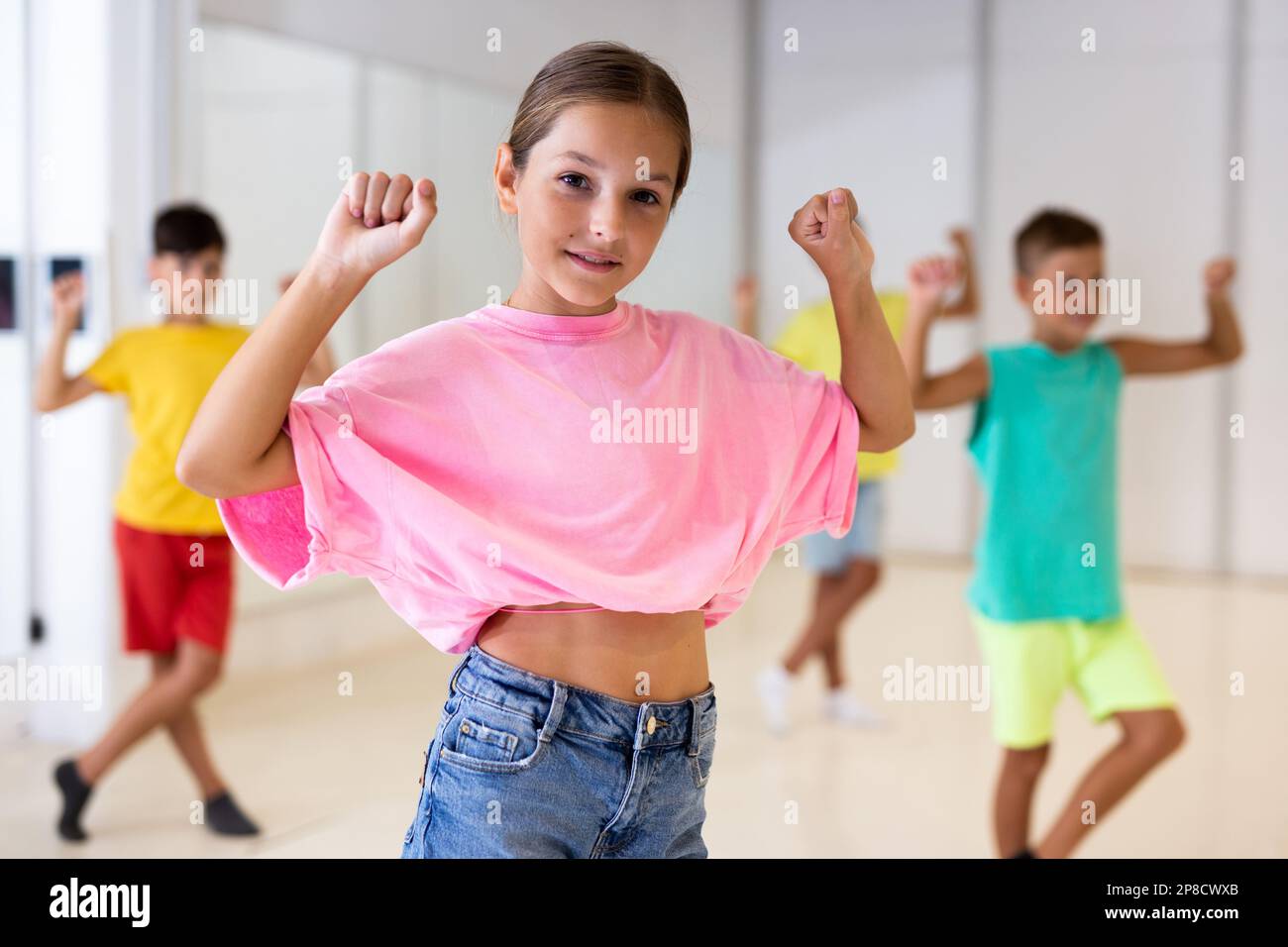 Smiling little girl training vigorous dance with group of tweens Stock ...