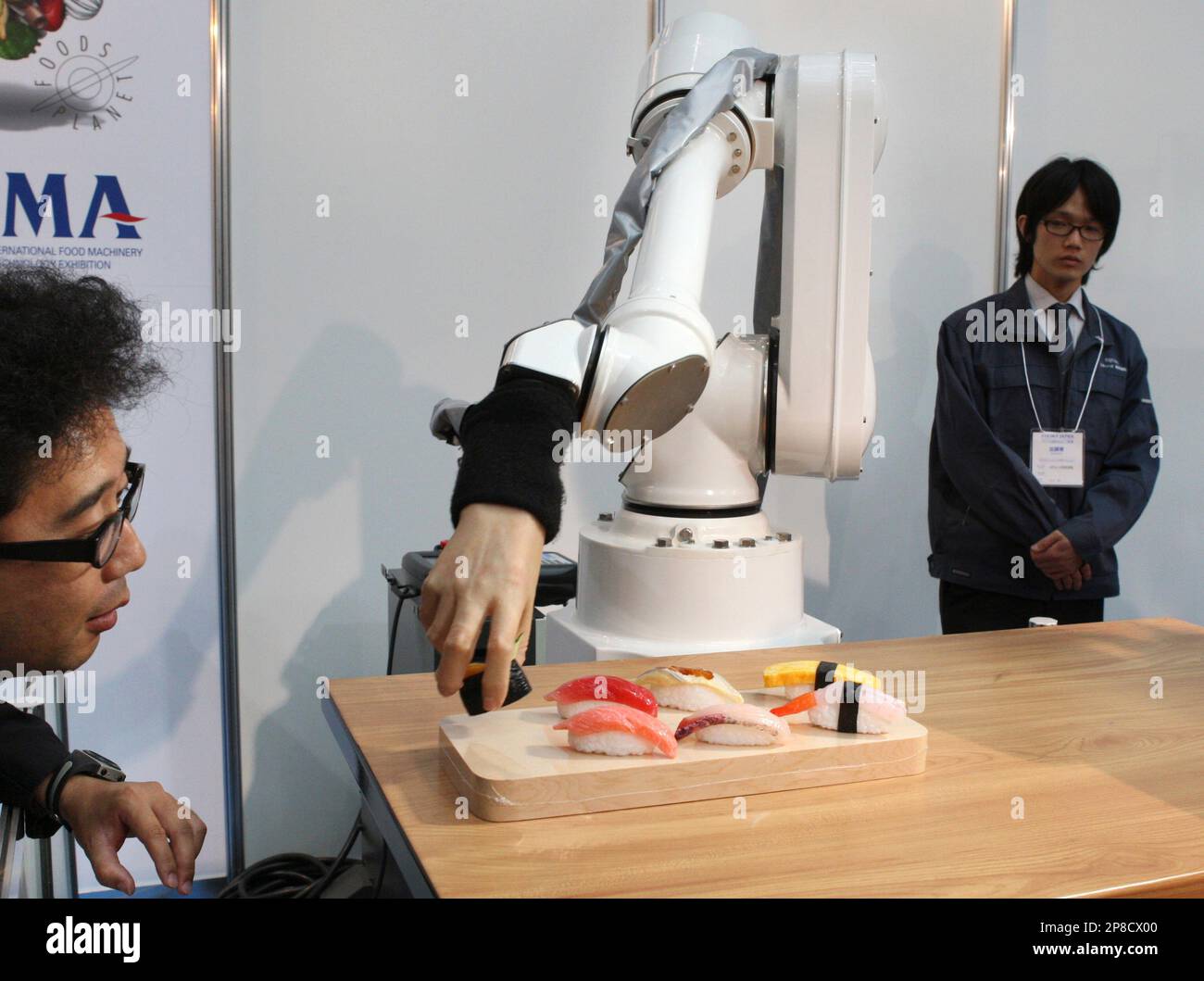 A visitor looks at Chef Robot, exhibited by Japanese food machinery ...