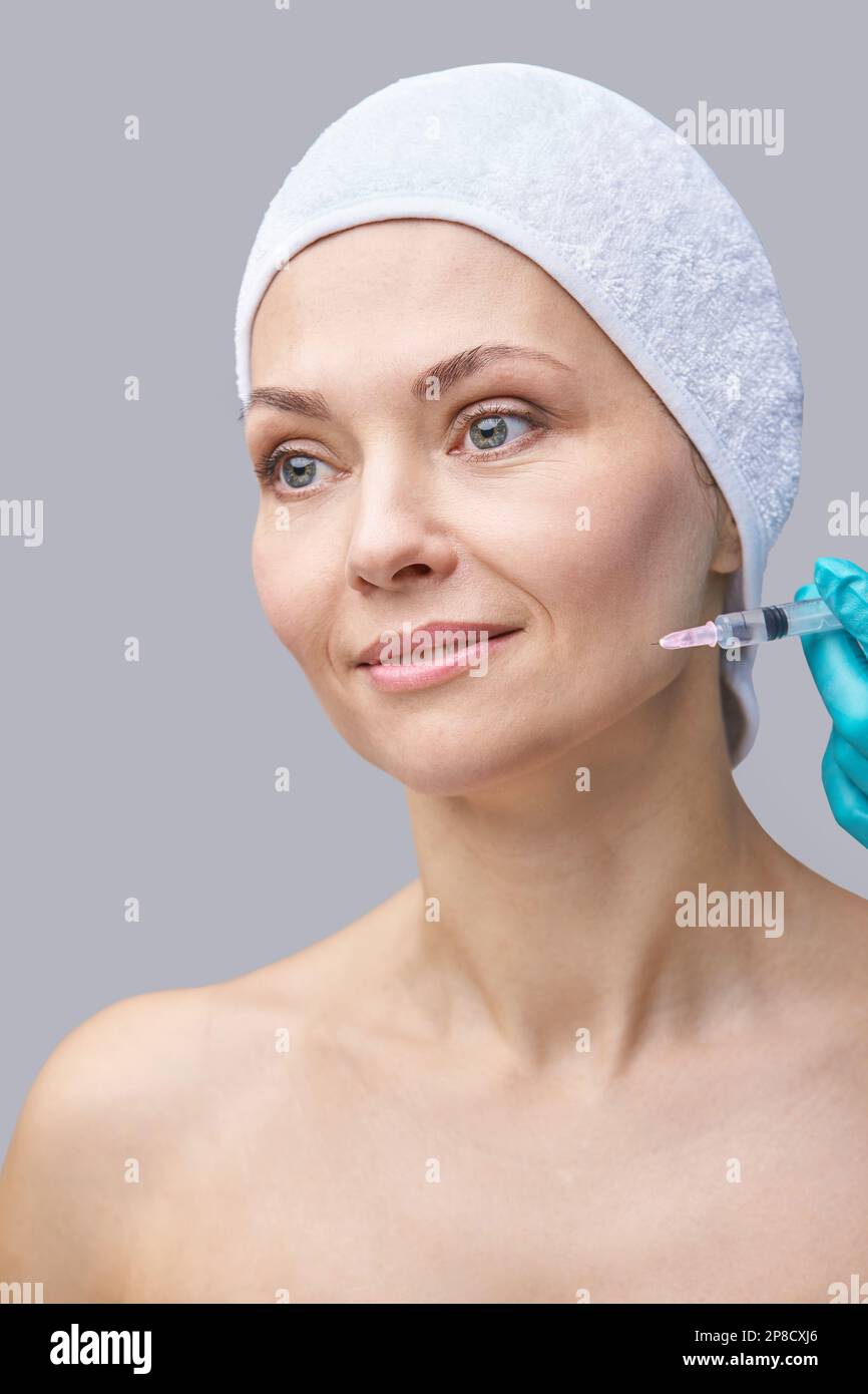 Face needle injection. Young woman cosmetology procedure. Doctor hand ...