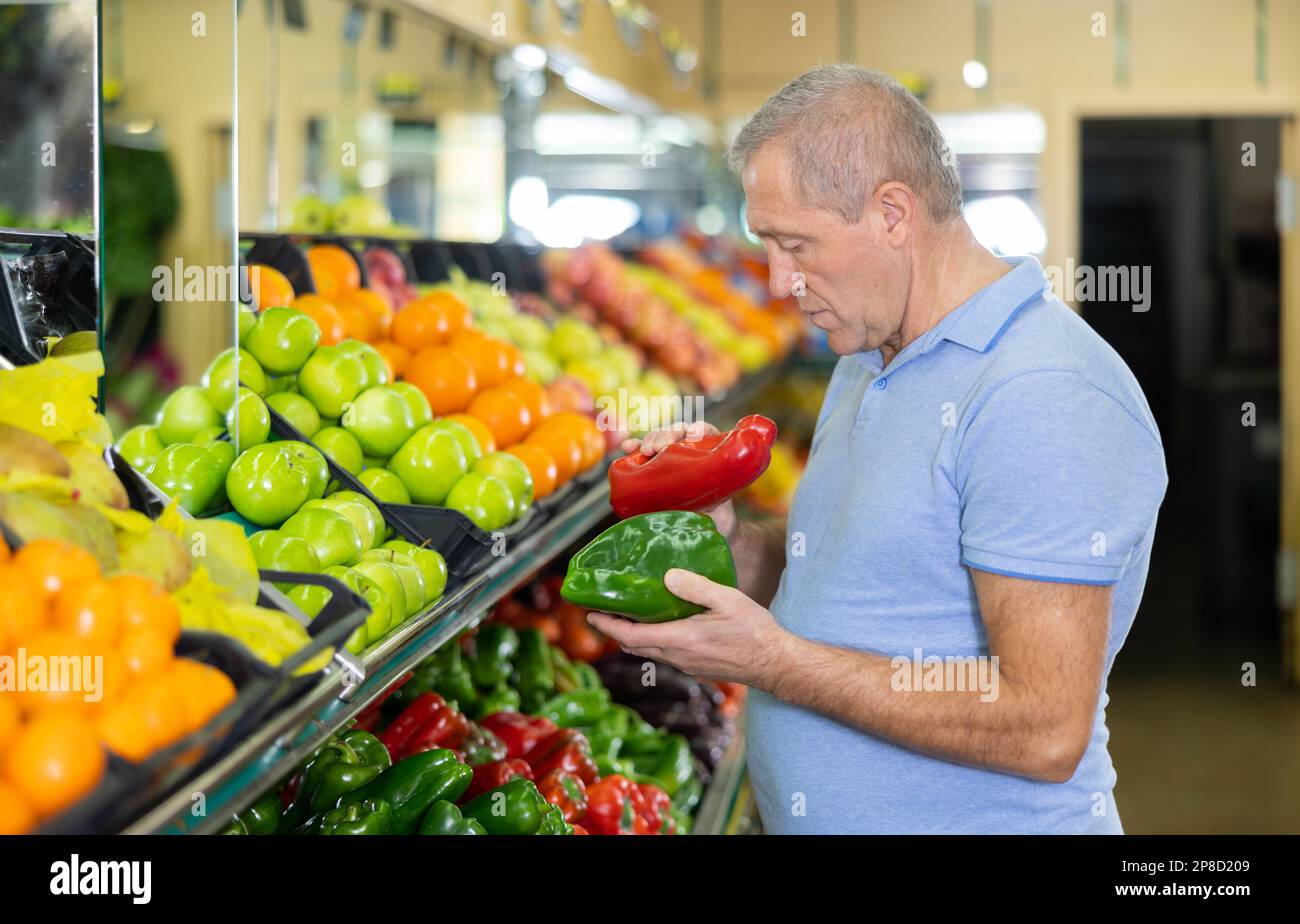 Busy old casual man pushing shopping cart and buying local bell peppers in grocery shop Stock ...