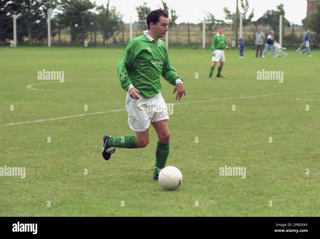 1989, amateur male footballer, in green kit, with ball at feet, playing ...