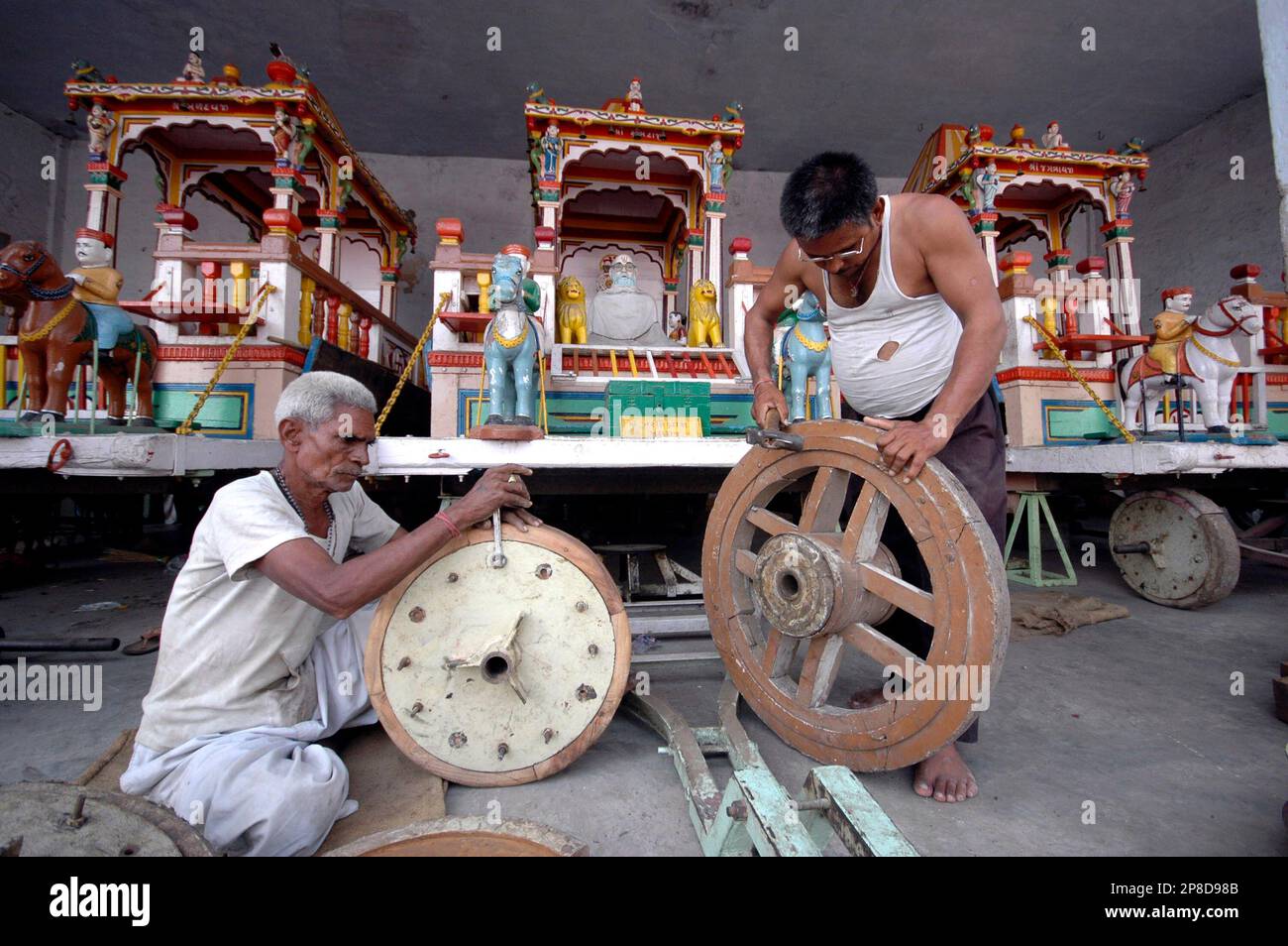 Laborers make chariot wheels for the Rath Yatra, an annual religious ...