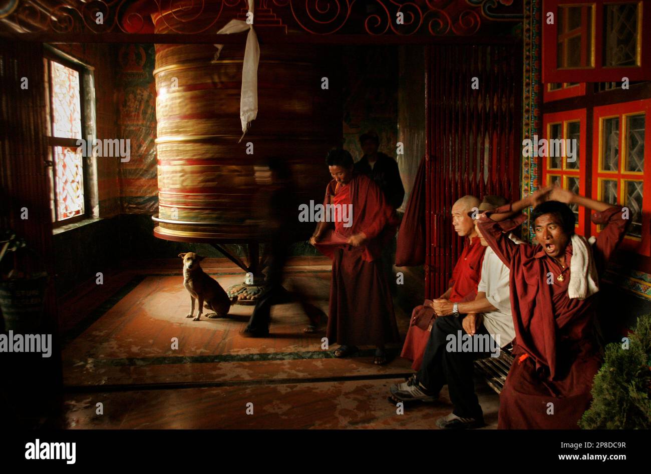 Tibetan Buddhists spin a giant prayer wheel, as others rest at a ...