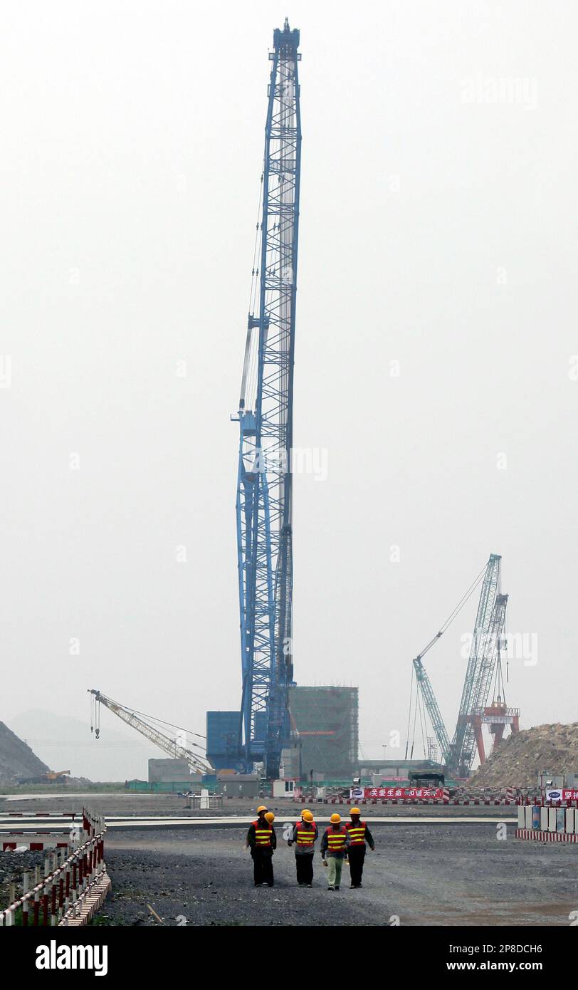 Workers walk near a large crane at the construction site of the Sanmen ...