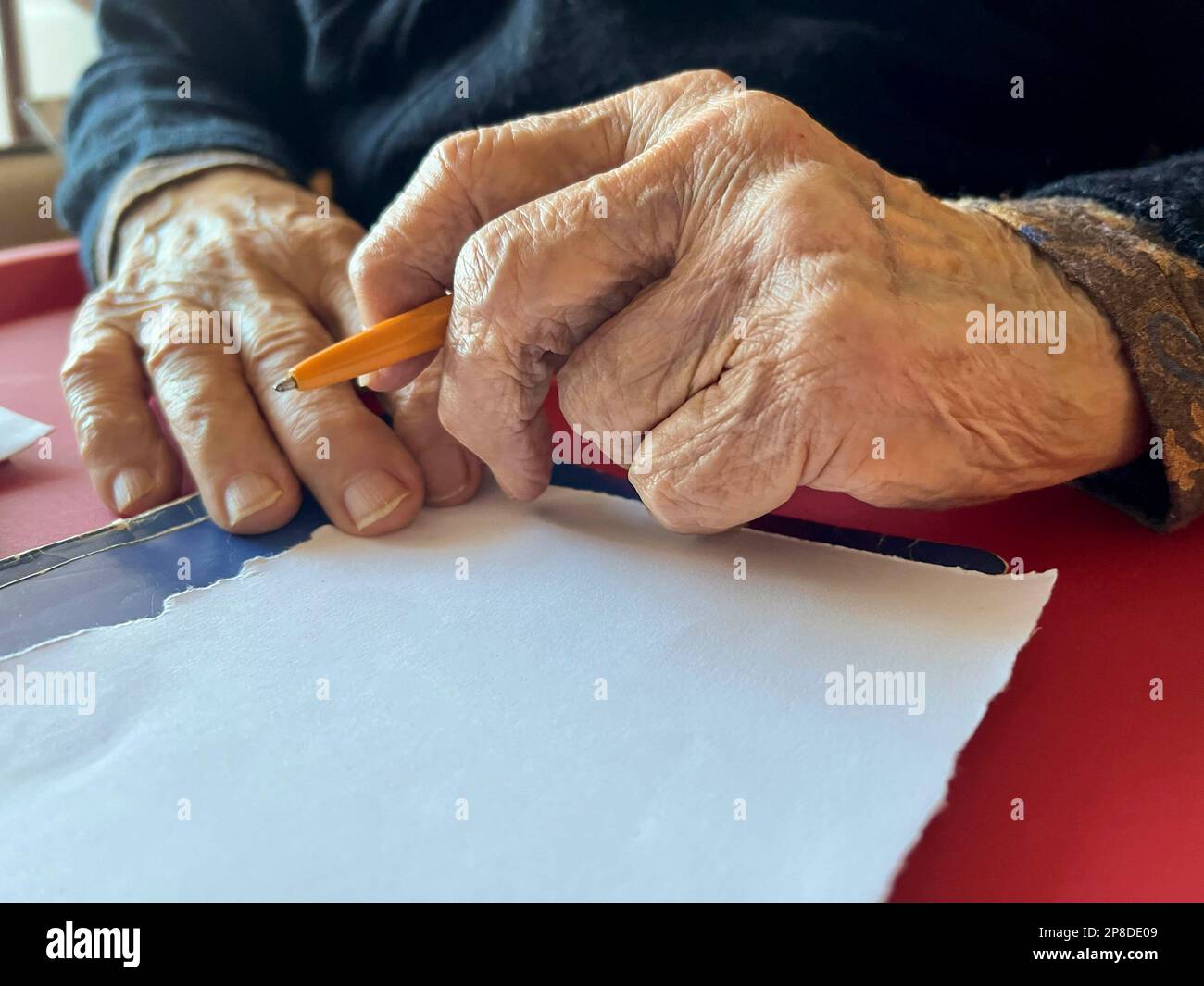 writing, closeup wrinkled hands of old person holding a pen to write on ...