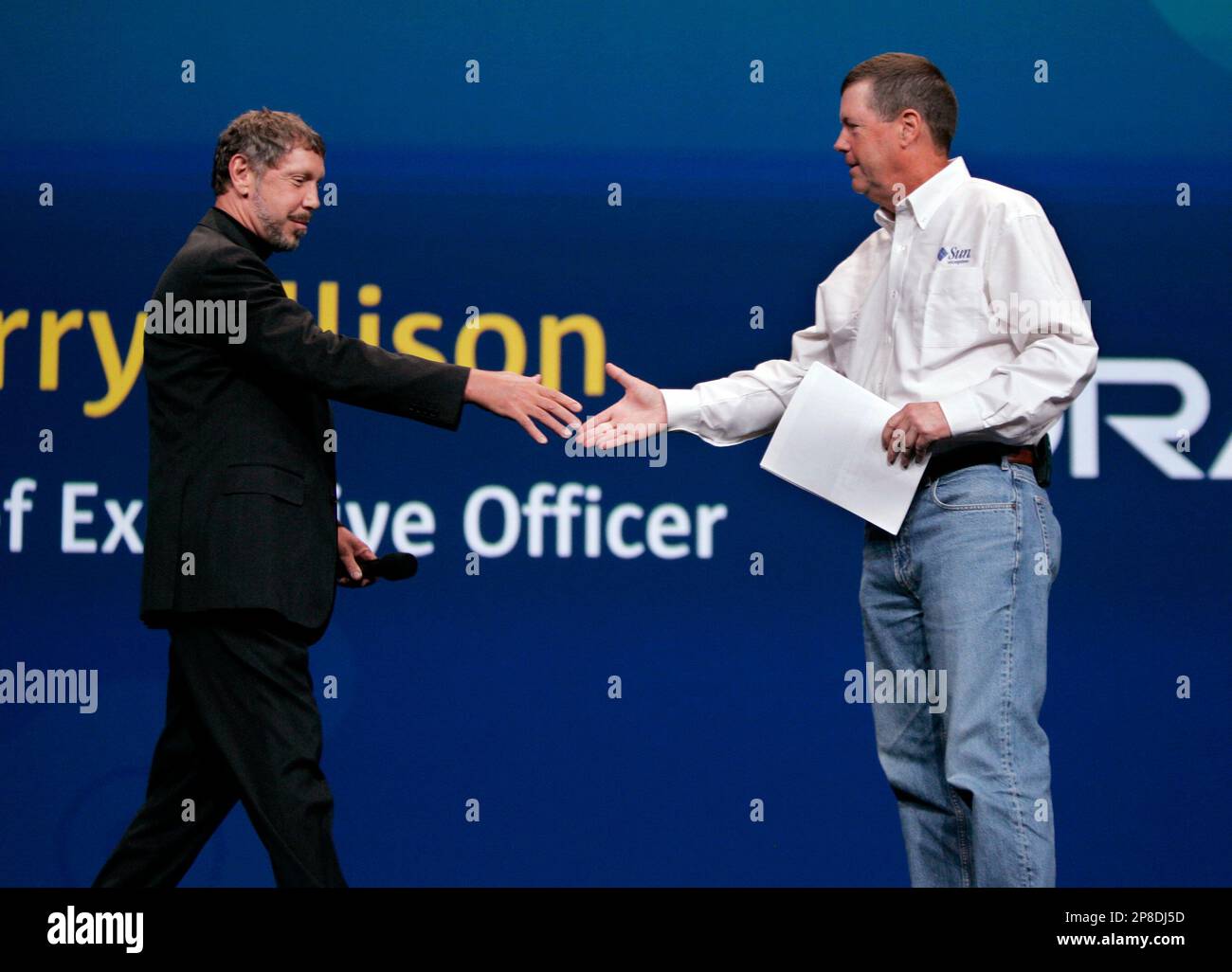 Oracle CEO Larry Ellison, left, shakes hands with Sun Microsystems co ...