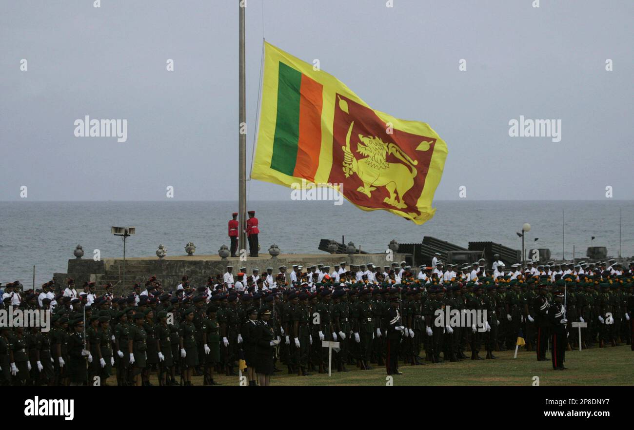 Sri Lankan soldiers hoist a national flag as others stand in honor ...