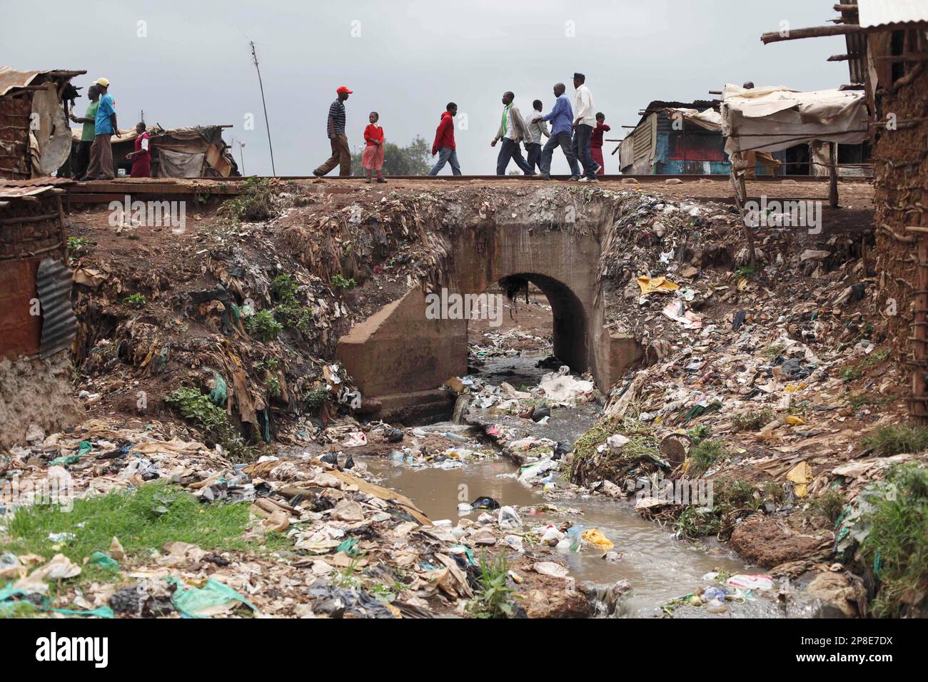 Slum dwellers cross a bridge over a stream of raw sewage, in the Kibera ...