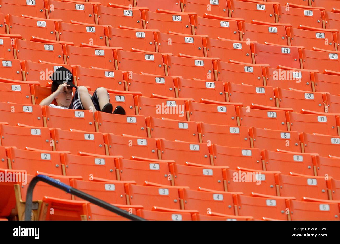 An unidentified fan sits amidst empty seats during a baseball game ...