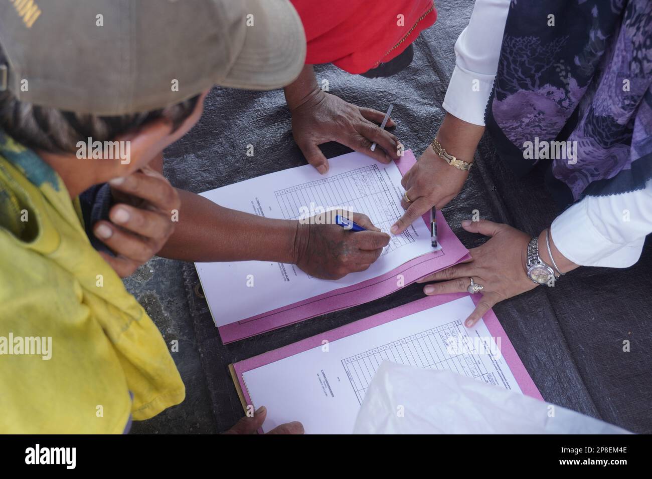 a group of people pointing at a paper while others are writing. taken ...