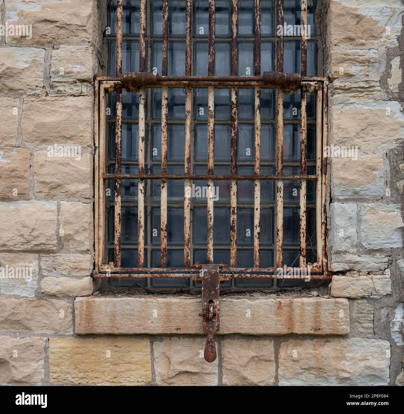 A close-up image of a small window with rusty metal bars across the ...