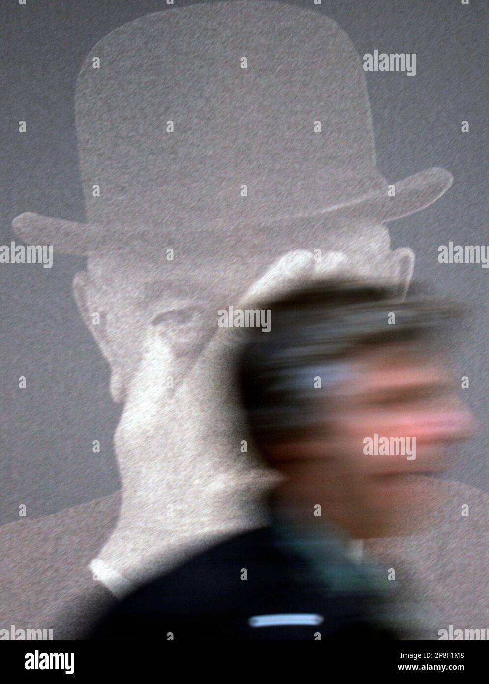 A man walks by a portrait of Belgian surrealist painter Rene Magritte ...