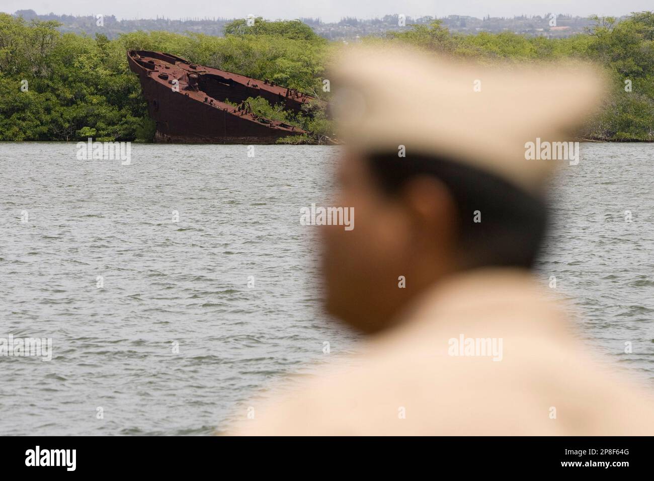 A naval official stands in a ship across from the remains of the USS ...