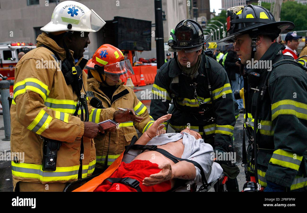 Paramedics and firefighters work with a plastic doll representing a ...