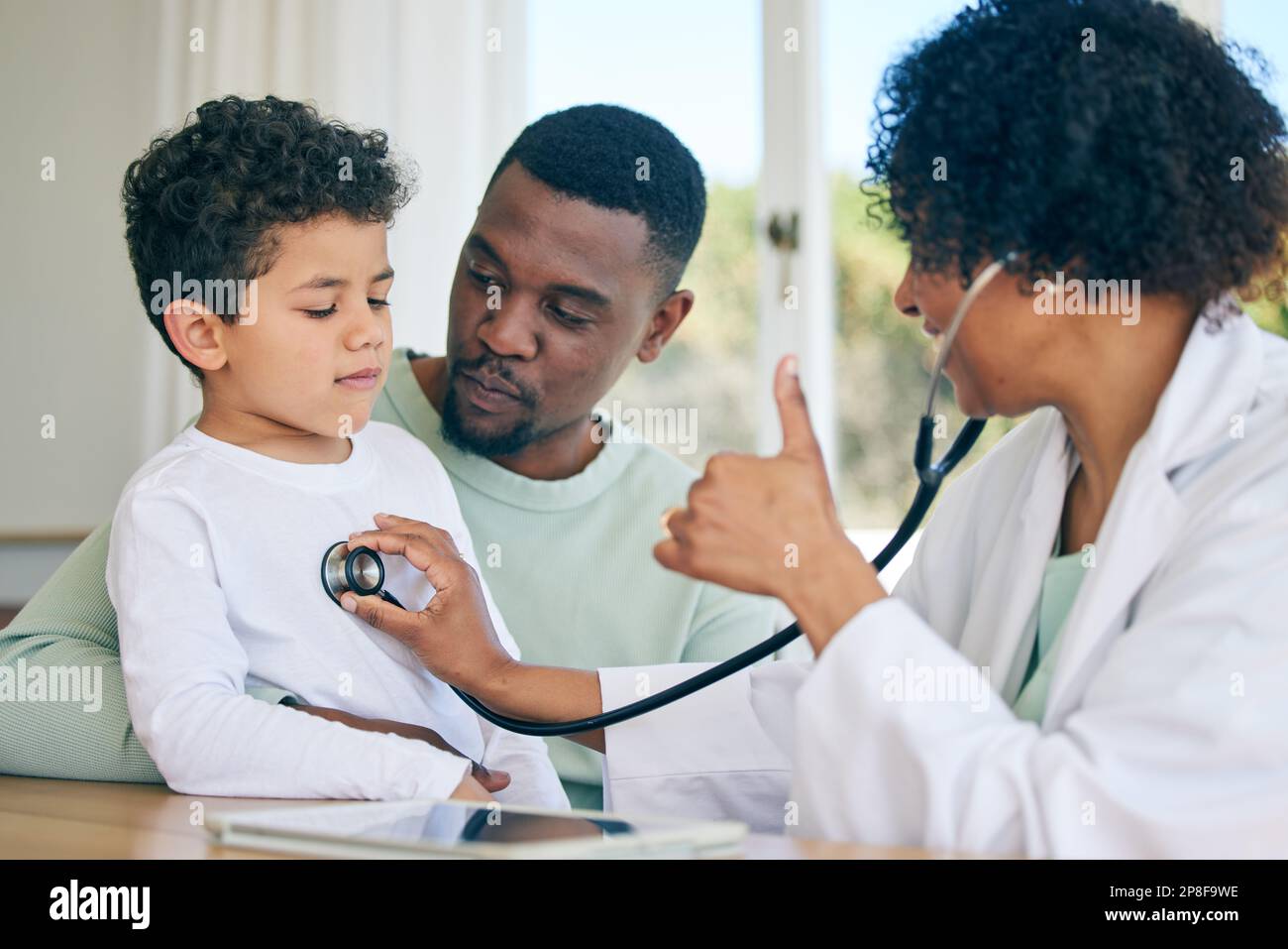 African dad, pediatrician with stethoscope and child in doctors office ...