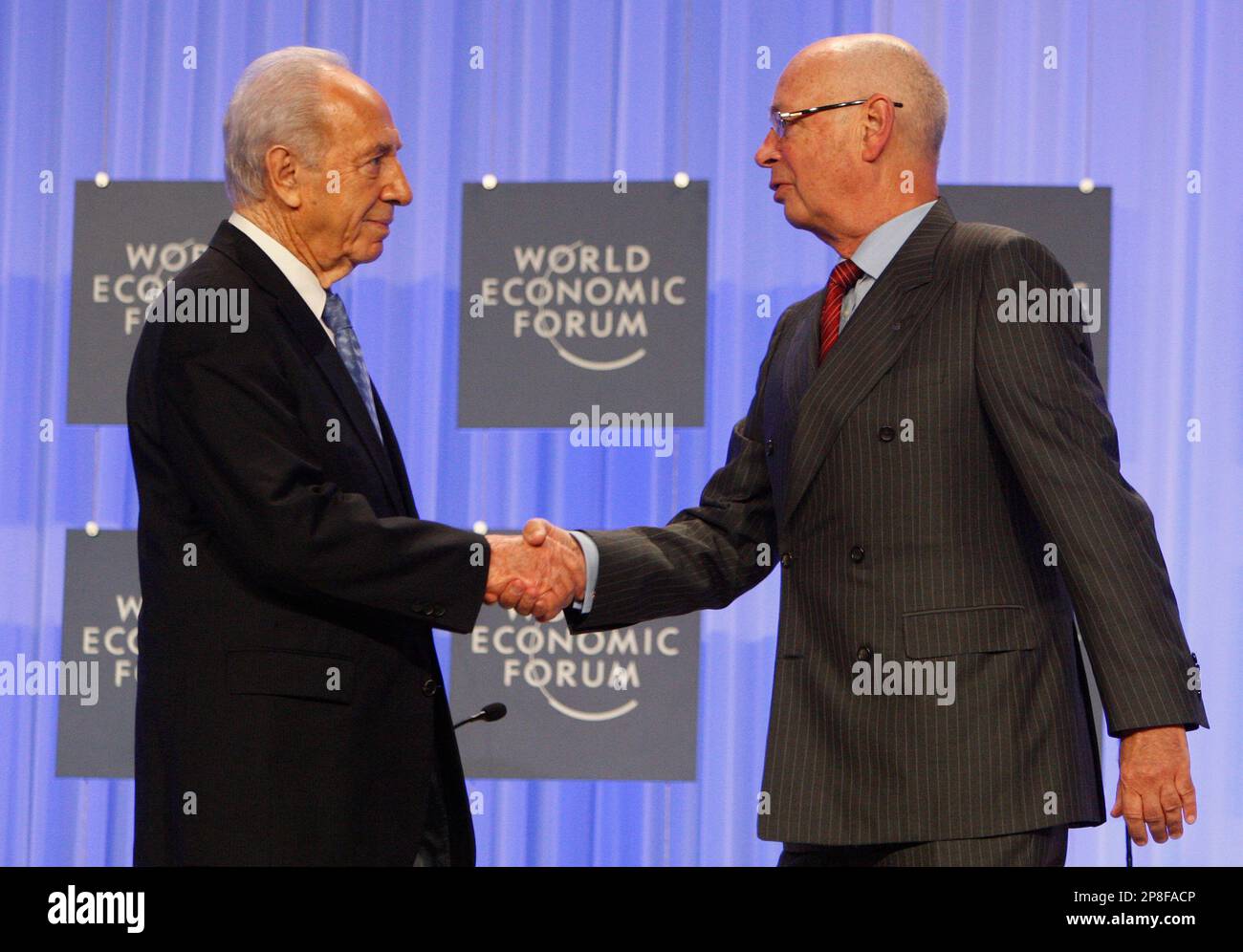 Israeli President Shimon Peres, left, shakes hands with Klaus Schwab ...