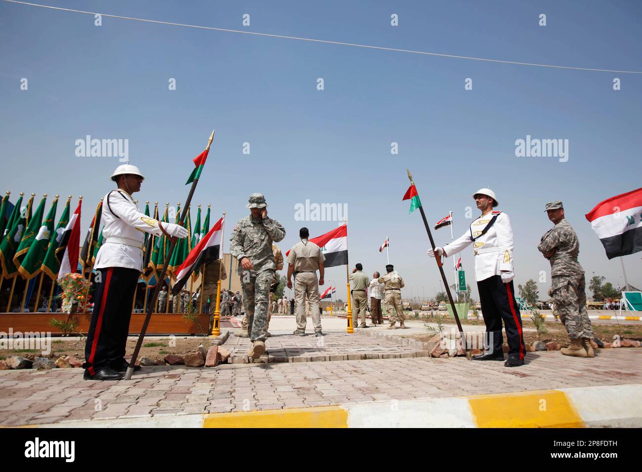A US soldier walks past two Iraqi soldiers in parade uniforms during a ...