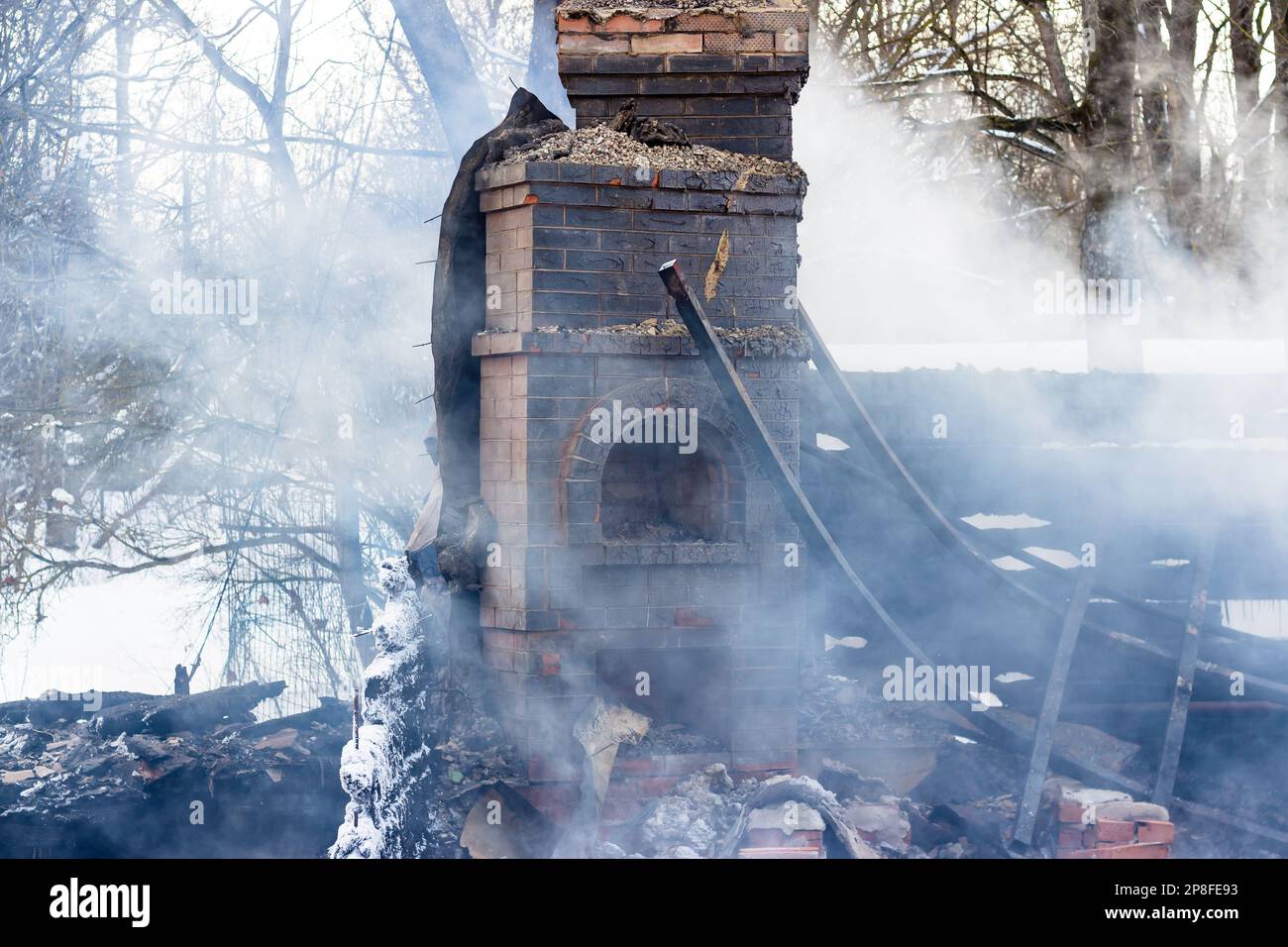 Brick oven at the site of the ruins of a burnt house, thick smoke after ...