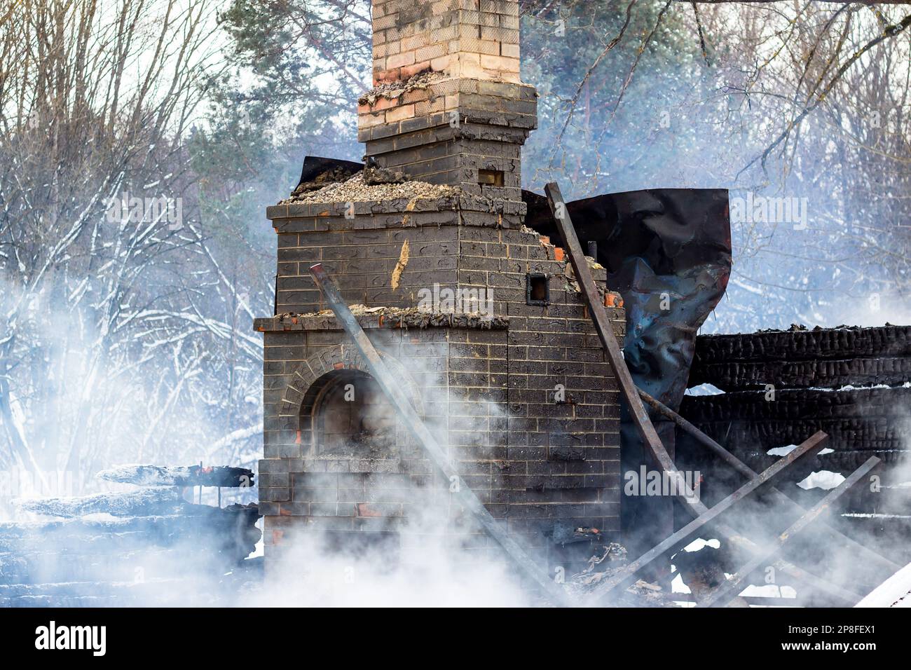 Brick oven at the site of the ruins of a burnt house, thick smoke after ...