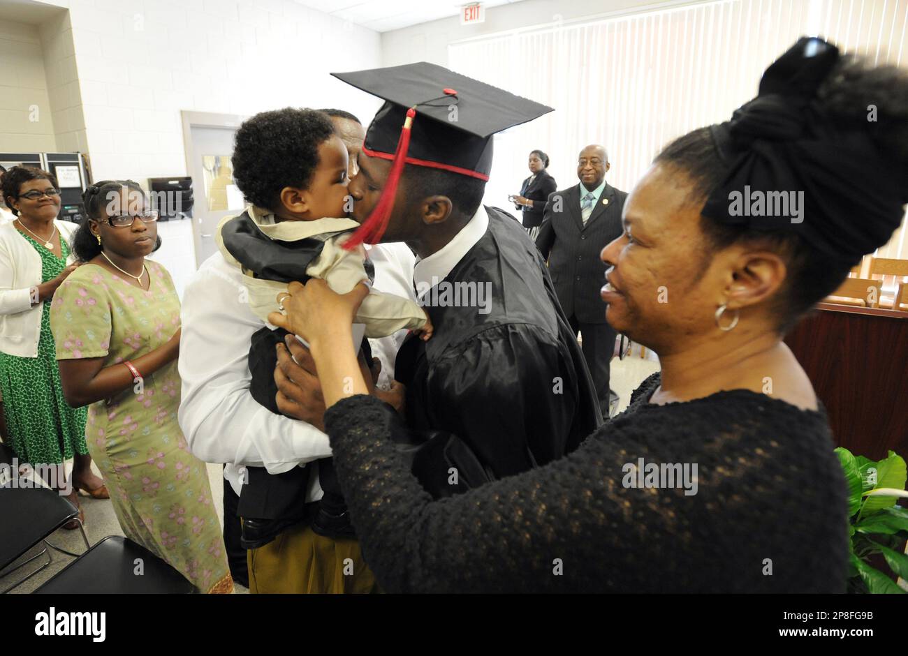 Robert Harris, 17, center, kisses his seven-month-old son Robert III ...