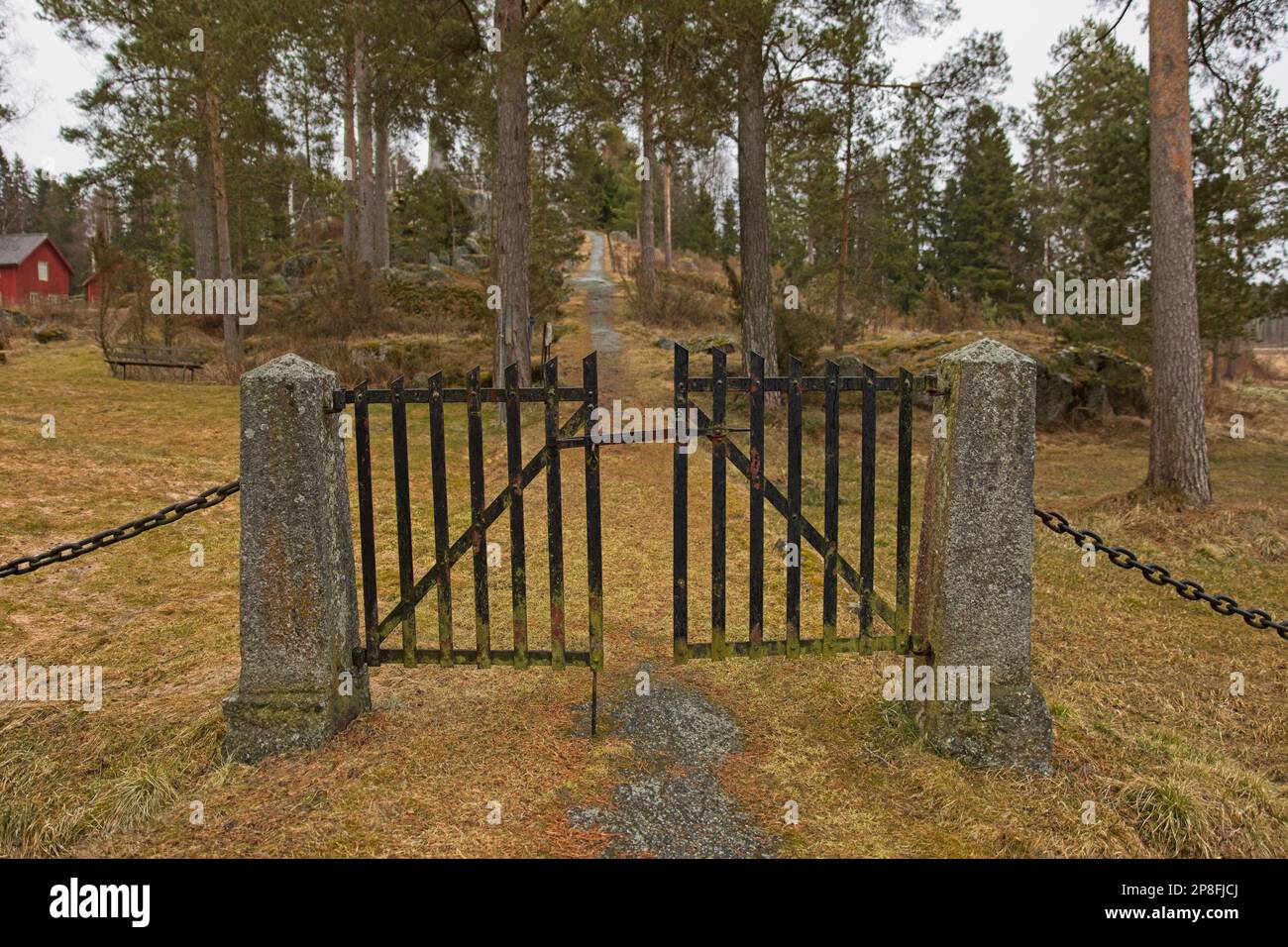 Old rusty wrought iron gate, leading to a dirt path to top of a hill ...