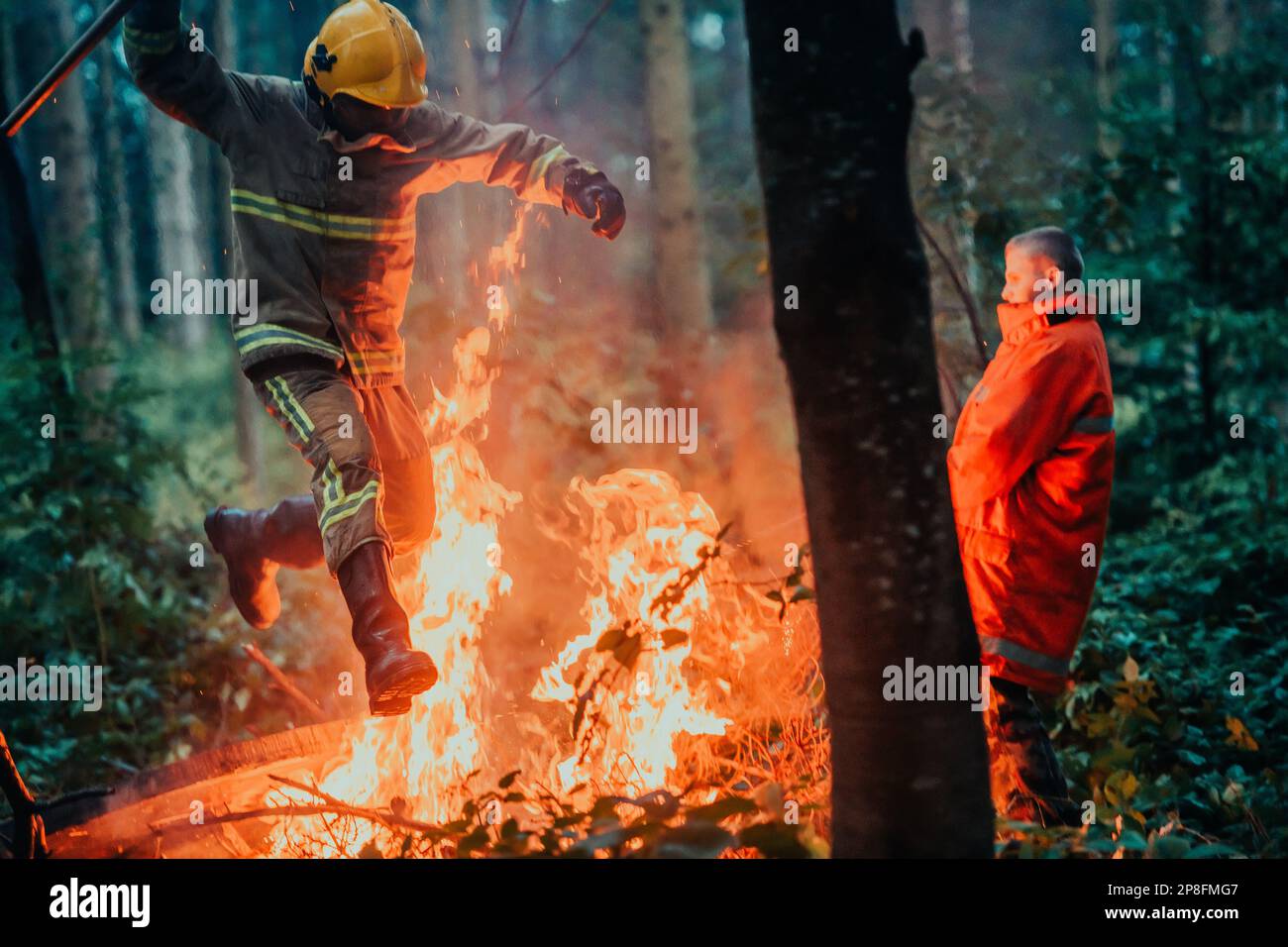 firefighter hero in action danger jumping over fire flame to rescue and ...