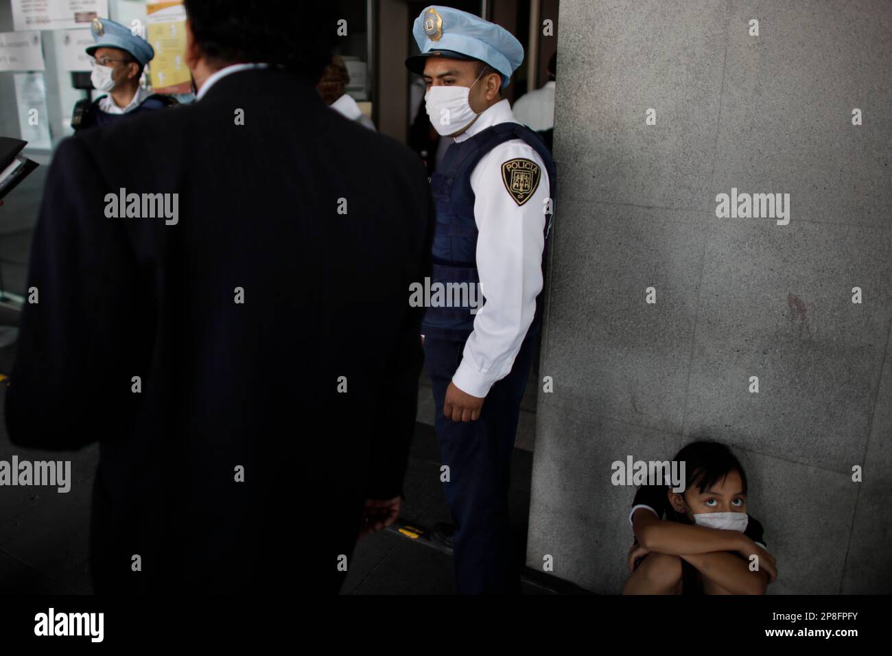 A girl, wearing a face mask as a precaution against swine flu, sits ...