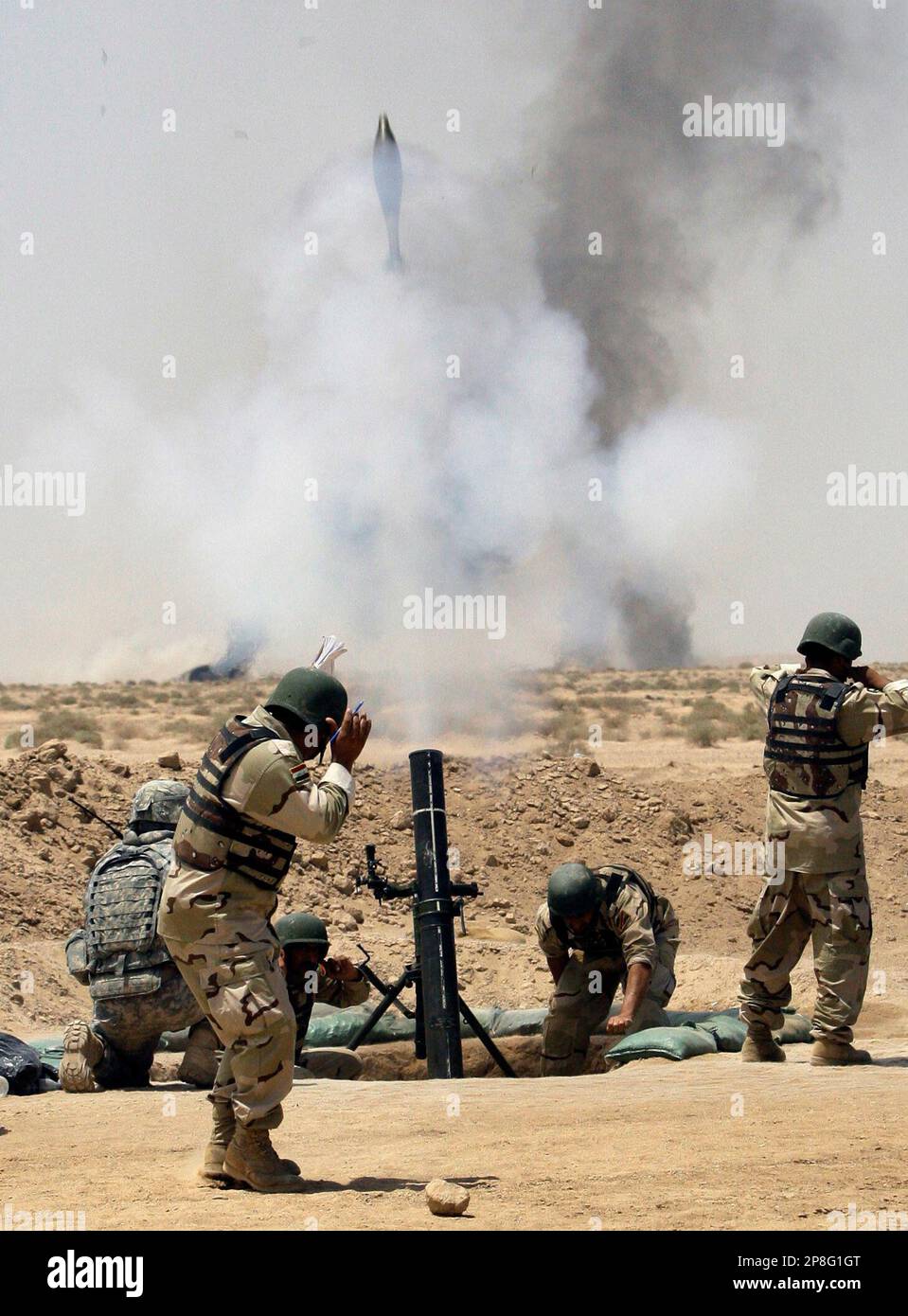 Iraqi Army and U.S. Army soldiers fire a mortar round as they ...