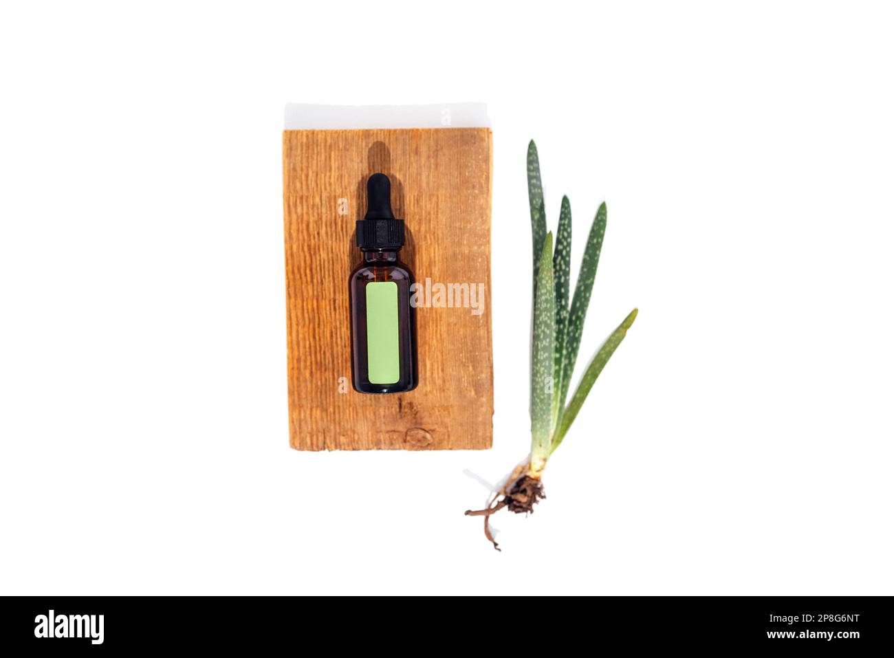 Mockup of a cylindrical serum shape with green stiker lies on a wooden ...