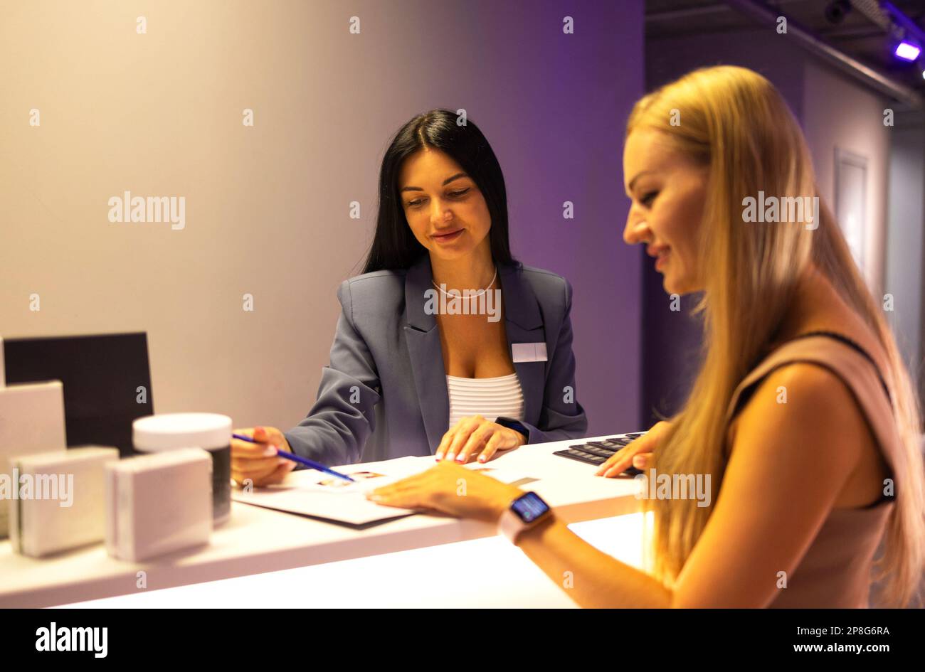 Smiling female client communicates with reception woman in a beauty ...