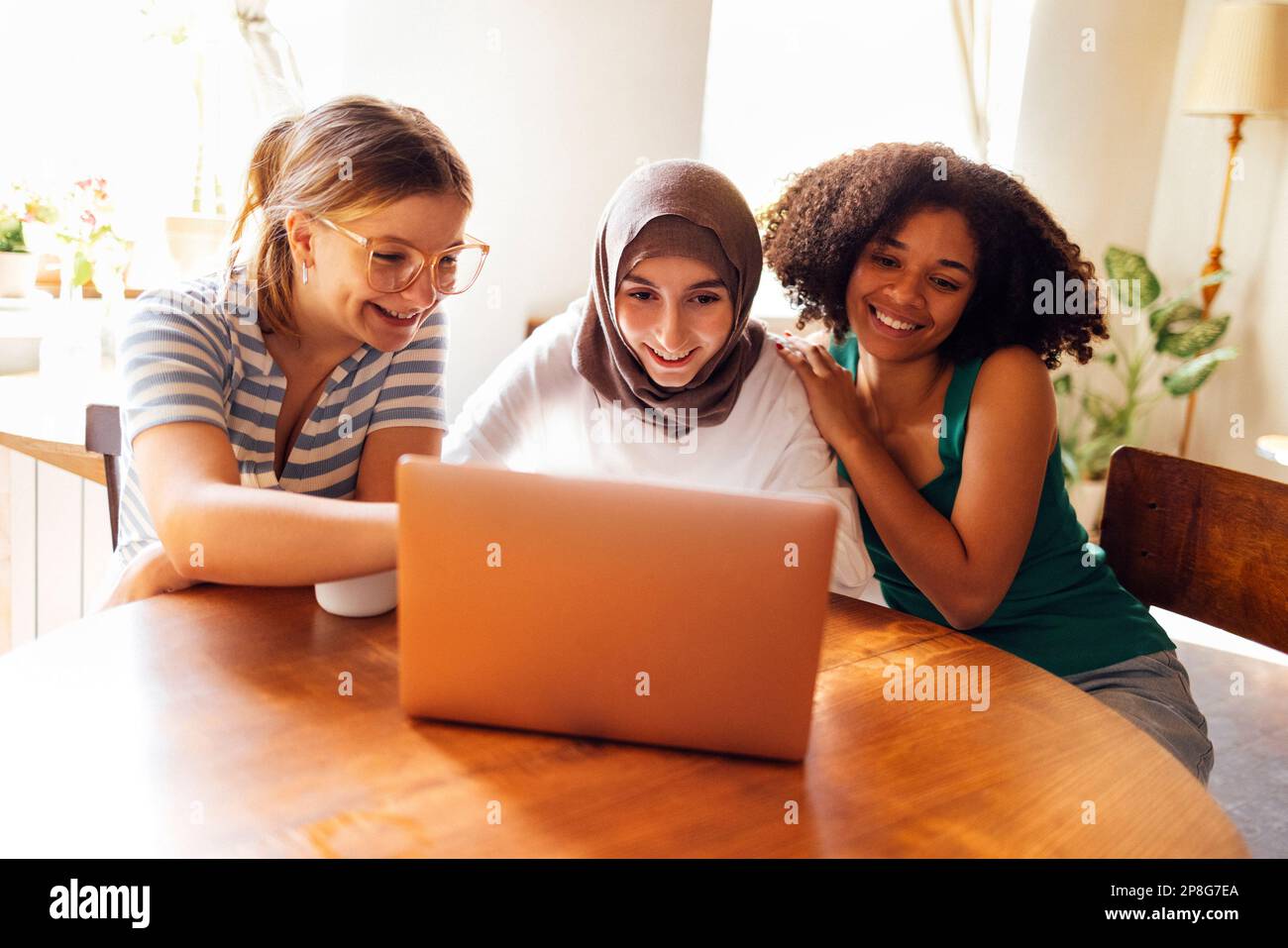 Three pretty female teenagers of different nationalities are looking at ...