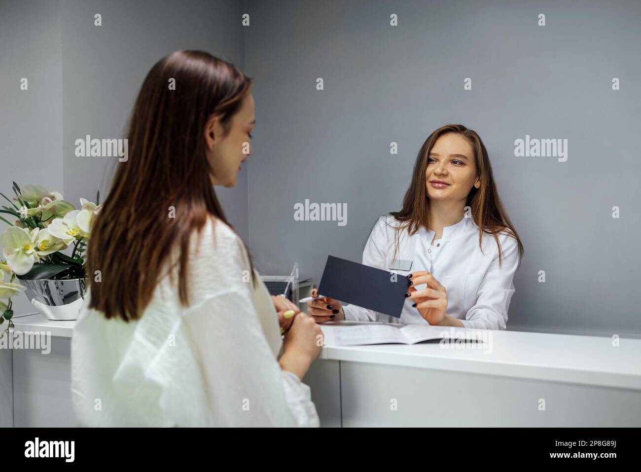 Smiling female client communicates with reception woman in a beauty ...