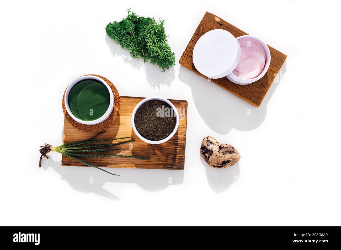 Plastic jar with green collagen eye patches on cork stage. Aloe plant ...